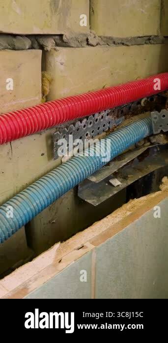 Close-up of red and blue plastic electrical conduits on old wall with ...