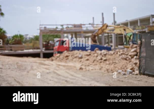 Blurry construction site with red truck and excavator in the background ...