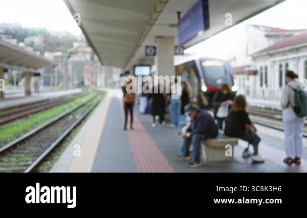 Blurred people waiting at a busy train station platform with a passing ...