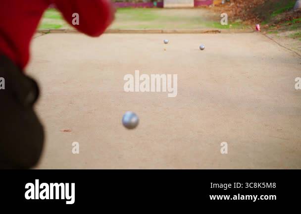 Petanque player throwing heavy metal boule with precision during ...