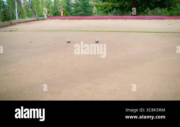 Metal bocce balls rolling smoothly across sandy court, capturing ...