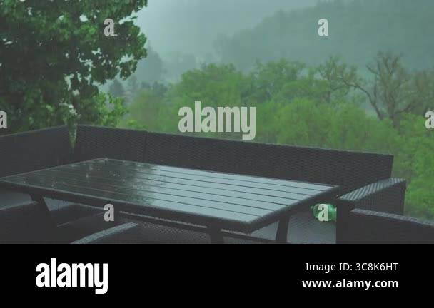 Outdoor patio furniture on a rainy day. The empty table and chairs are ...