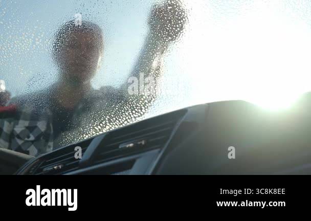 Male washing windshield in sunlight, view from from car inside. Man ...