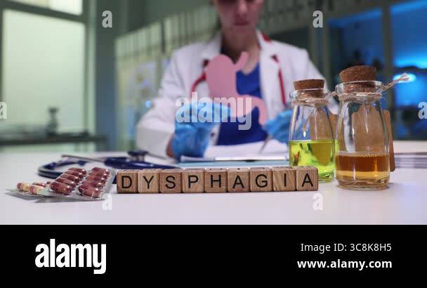 A doctor studying dysphagia with pills, liquids, and anatomical model ...