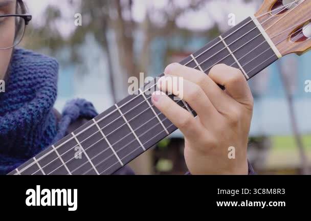 Musician's hand frets notes on a classical guitar's fretboard. Extreme ...
