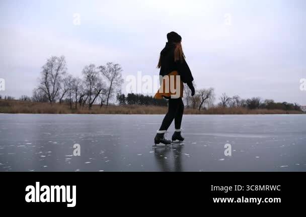 Female skater skating on frozen river at cloudy day. Woman shod in ...