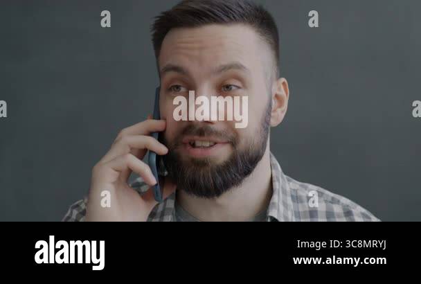 Young man speaking on mobile phone making cellphone call on black color ...