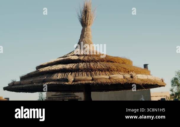 A traditional parasol crafted from natural straw stands tall against ...