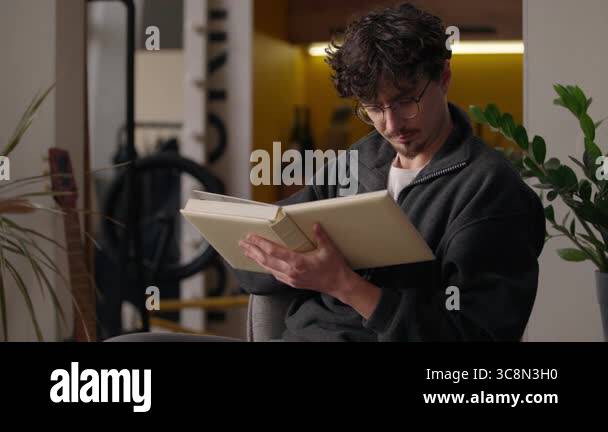 Focused Caucasian guy reading book at home hipster male read story ...