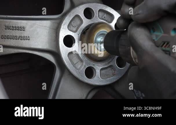 Mechanic using a drill-mounted wire brush to clean the center bore of ...