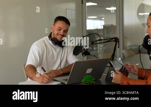 Two radio hosts using laptop and discussing during a live podcast ...