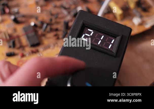 Hand turns a knob on an electronic device, causing the digital display ...