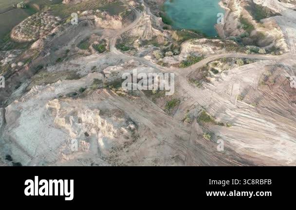 Aerial drone footage of a small rock quarry flooded into a small lake ...
