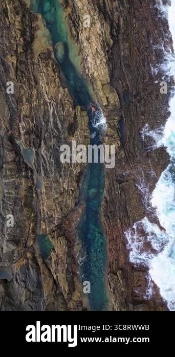 From above a distant woman swims in the natural green pools of Tindaya ...