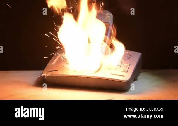A landline phone is engulfed in bright flames and sparks during a fire ...