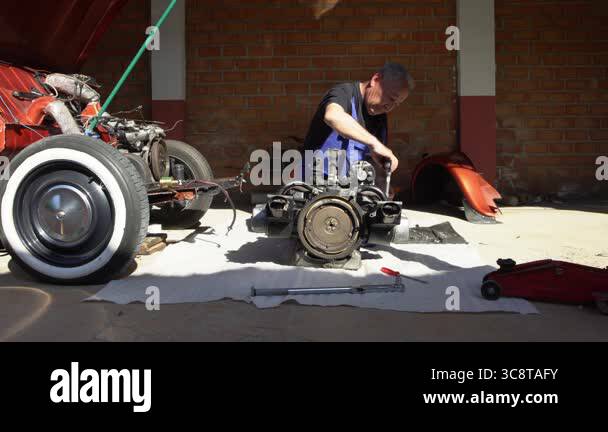 Two mechanics collaborate to repair a motor in a rustic Spanish garage ...