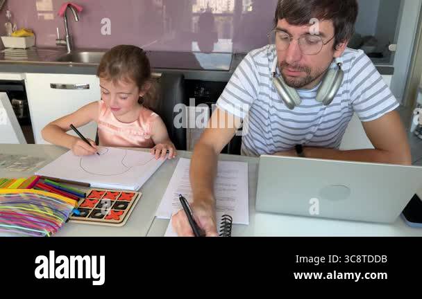 Dedicated father multitasking during remote work, focusing on laptop ...