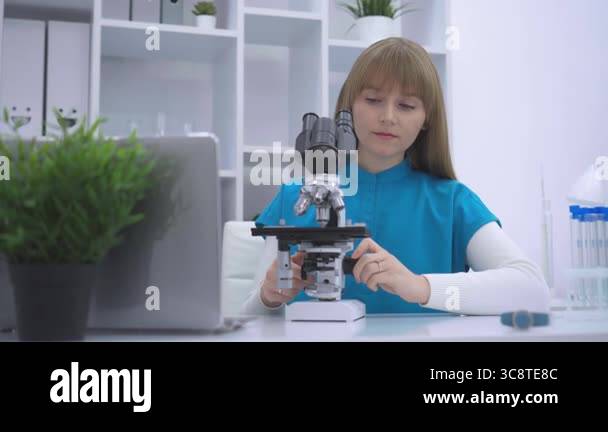 Woman scientist in blue uniform and lab coat working with microscope in ...