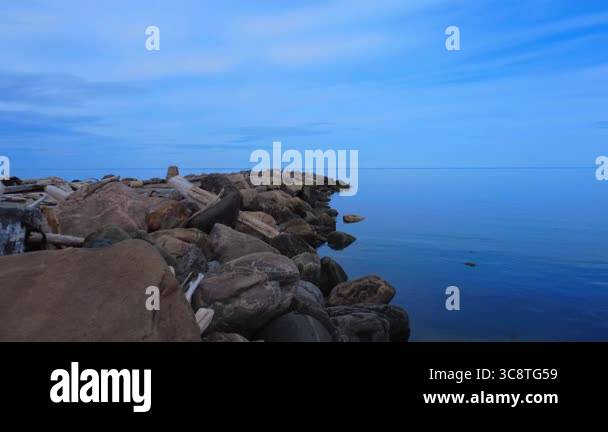 An old, neglected rocky dock piled with sea lumber juts out into the ...