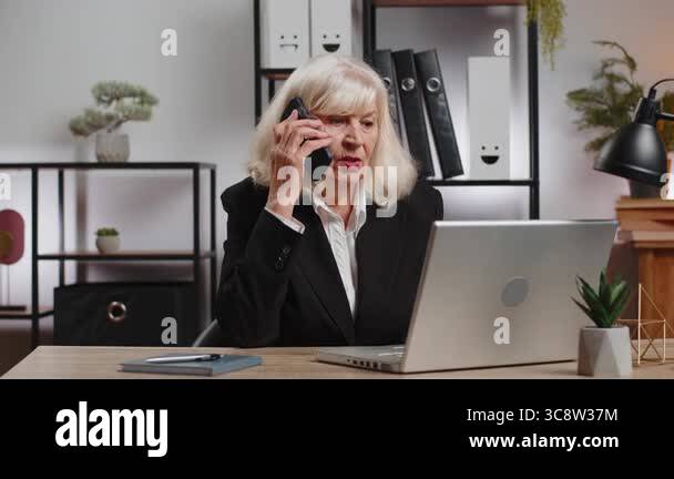 Confident senior Caucasian businesswoman operator grandmother communicating with client by ...