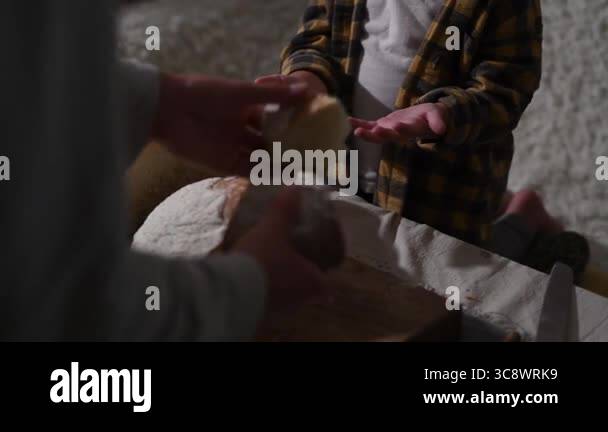 Father breaks bread piece and offers it to daughter, hands and bread ...