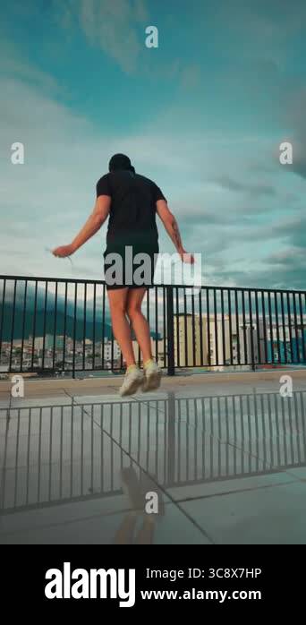 Man bodybuilder jumping rope on rooftop during sunset workout, Athlete ...