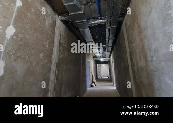 Grey walls of the long corridor in the constructed building. Low angle ...