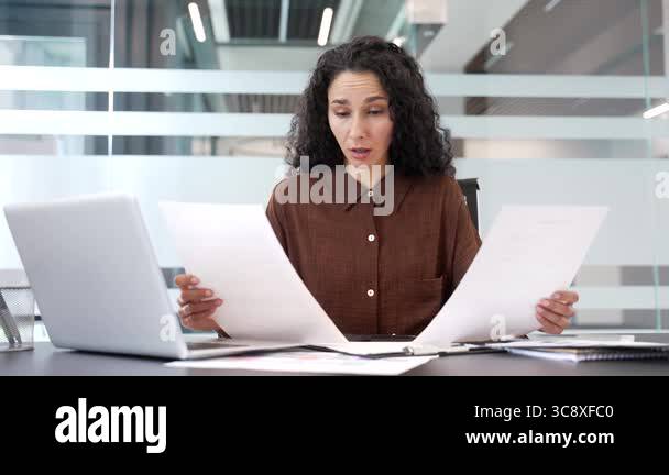 Confused businesswoman having difficulty with paperwork sitting at ...