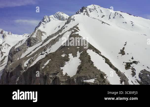Aerial view of rugged, snow-capped mountain peaks under a blue sky in ...