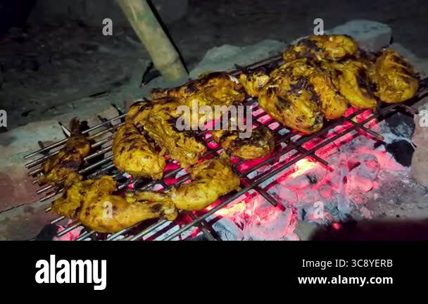 Barbecue chicken grilling over glowing coals in outdoor setting at ...