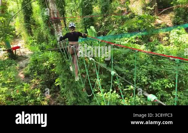 A man and a woman is walking across a challenging ropes course in the ...