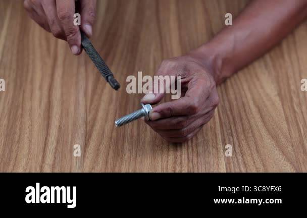 Mechanic hand clean and fix the threads bolt with a thread file, is a ...
