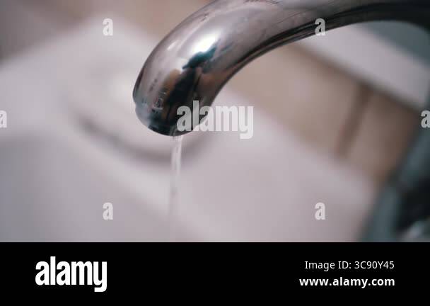 A gentle stream of water flows from a bathroom faucet, ideal for ...