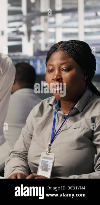 Vertical video Data center team leader and IT expert reviewing performance dashboards of AI ...