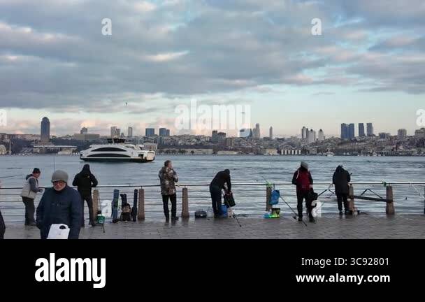 Fishermen line the waterfront, casting lines as boats glide by Stock ...