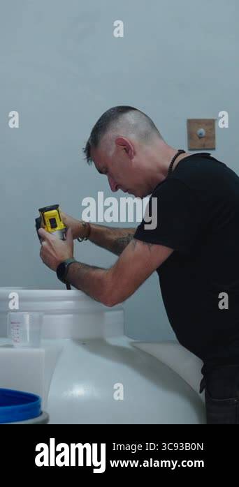 Technician working in a large white water tank mixing liquids with the ...