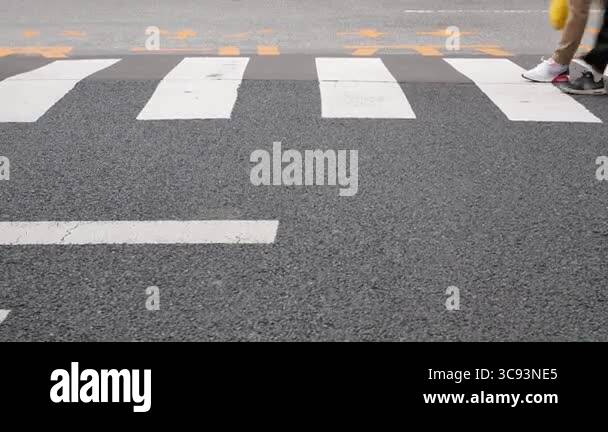 Crowd of pedestrians crossing a city street in low angle view of legs ...