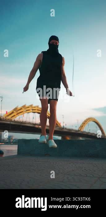 Man bodybuilder jumping rope at river shore during sunset workout ...