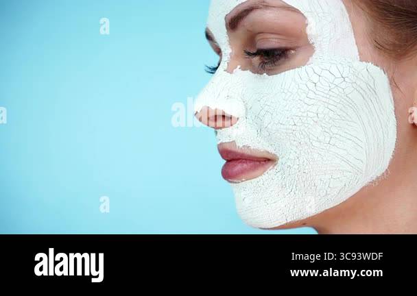 Young woman with white dry mud mask on her face, against blue. Teen ...