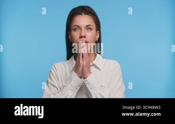 Woman with hands together in a prayer gesture, looking upward with ...