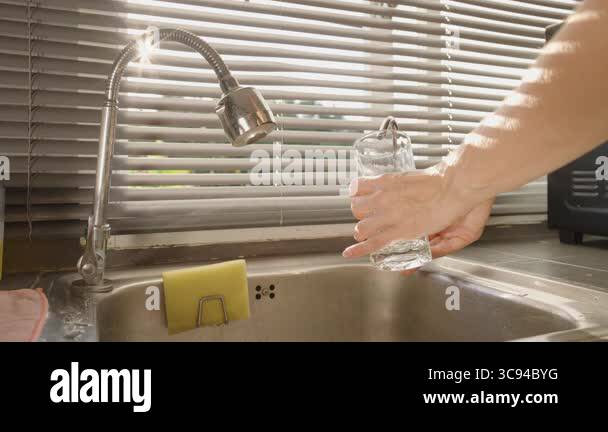 Hand Filling Glass with Drinking Water from Filter Faucet over Kitchen ...