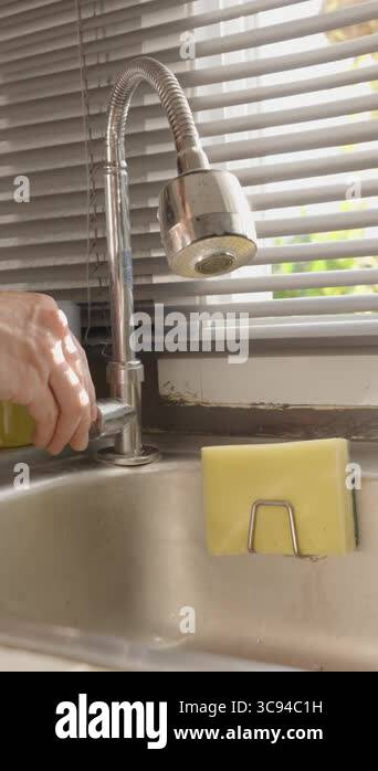 Vertical video. Hand Turning On Faucet with Water Running in Stainless ...