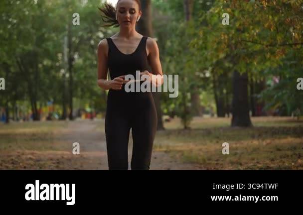 Slow motion. A dynamic runner in a beautiful park is showcasing ...
