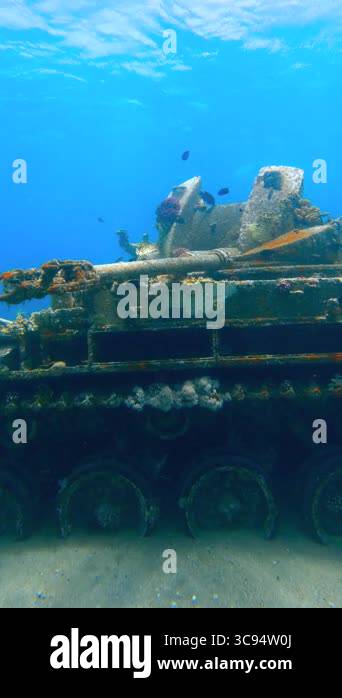 Underwater view of a sunken military tank sitting on the sandy seabed ...