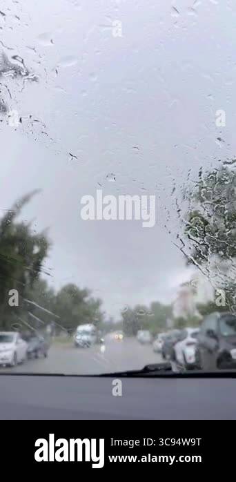 Driving a car in the city during a rainstorm. Raindrops on window car ...