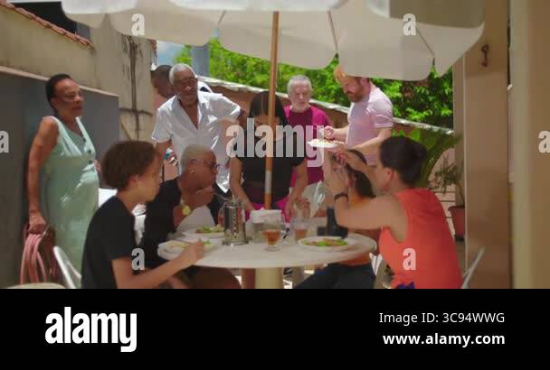 Multicultural family gathering at outdoor dining table, sharing meals ...
