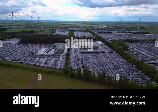 Aerial view of a large parking lot full of cars near a wind farm and ...