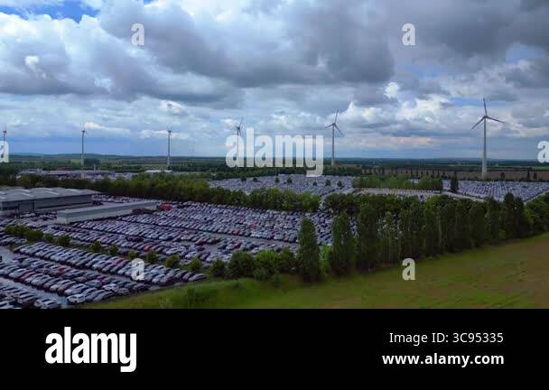 Aerial view of a large parking lot full of cars near a wind farm and ...
