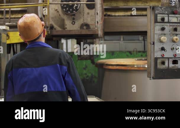 Factory worker wearing safety helmet monitors machinery operation Stock ...