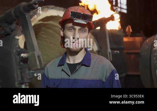 Industrial worker wearing uniform and helmet communicating near furnace ...
